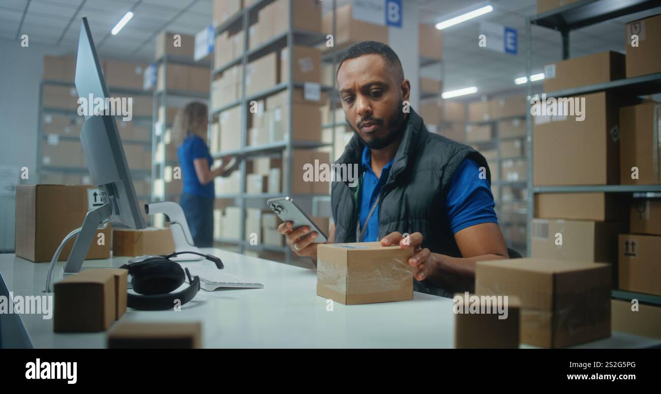 African American logistics manager scans parcels using smartphone, works in postal service ...