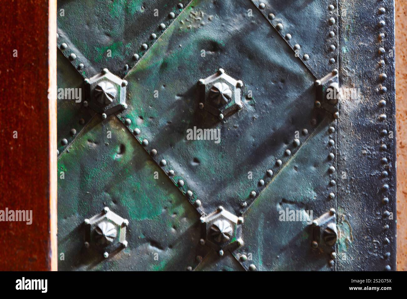 Weathered metal surface with a diamond pattern, featuring rivets and ...