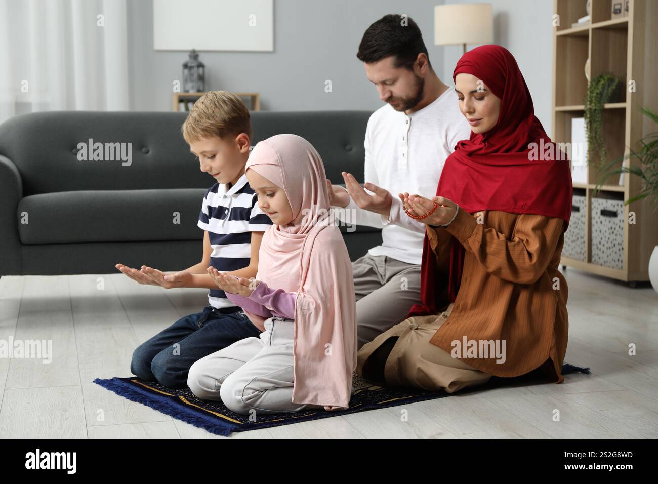 Happy Muslim family praying on mat at home Stock Photo - Alamy