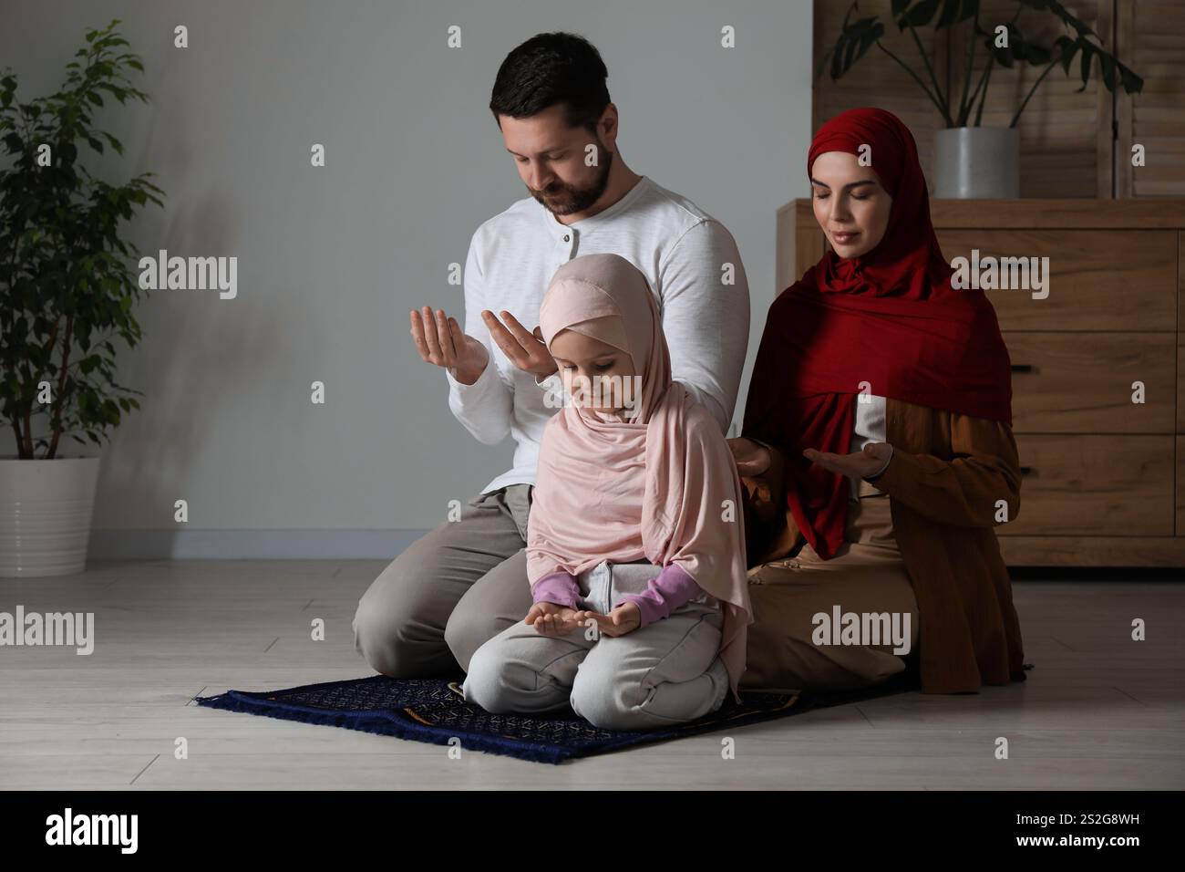 Muslim family praying on mat at home Stock Photo - Alamy