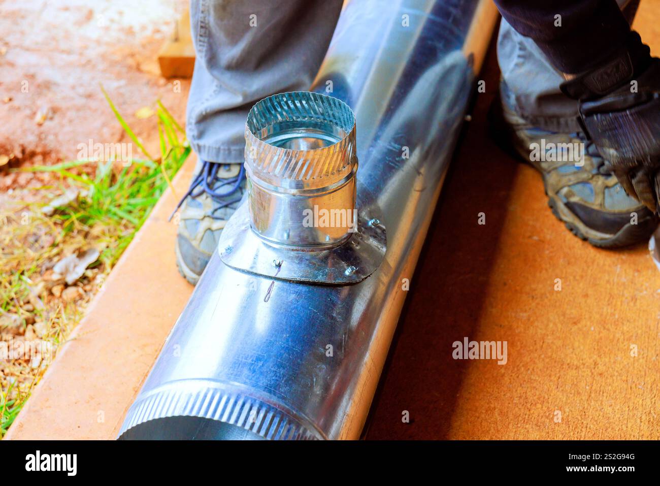 Worker attaches circular metal HVAC fitting to ventilation pipe while ...