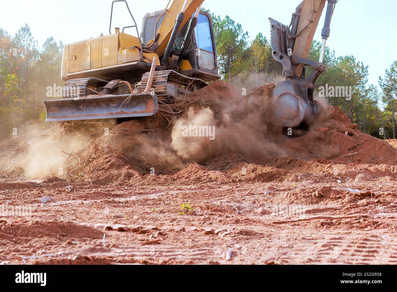 Large excavator digs into earth at construction site, sending clouds of ...
