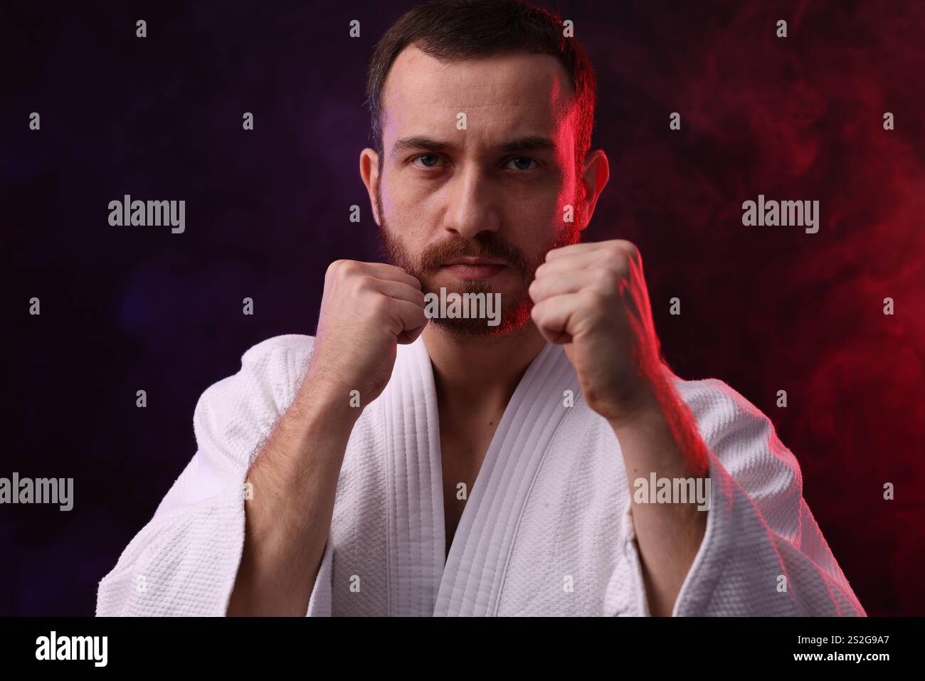 Karate fighter in color lights and smoke against black background Stock ...