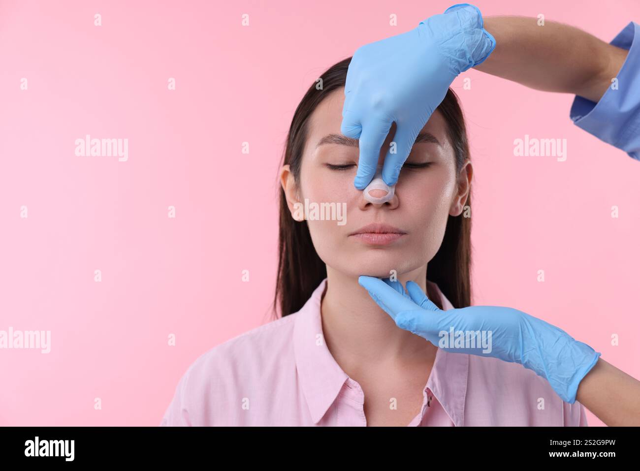 Doctor checking patient's nose after plastic surgery operation on pink ...