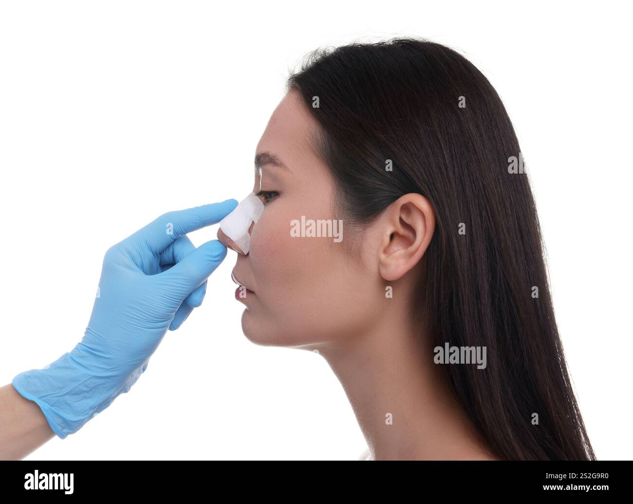 Doctor checking patient's nose after plastic surgery operation on white ...