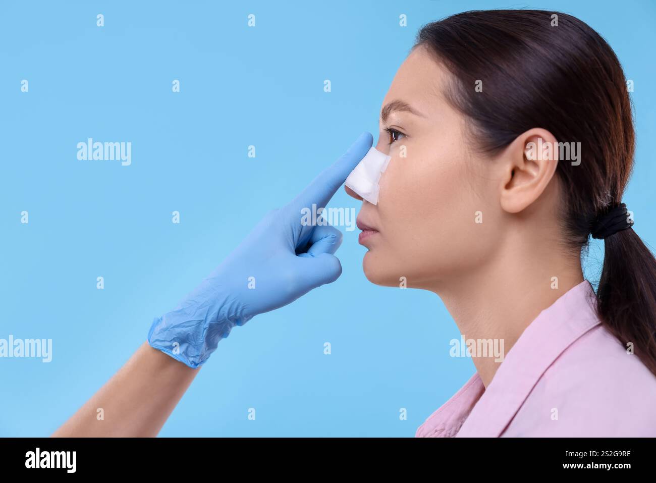 Doctor checking patient's nose after plastic surgery operation on light ...