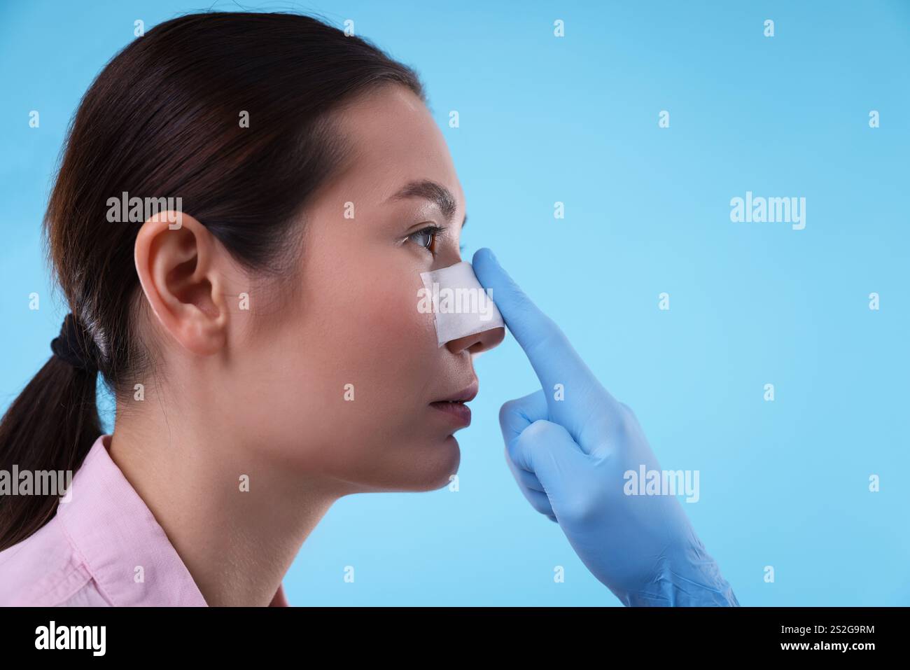 Doctor checking patient's nose after plastic surgery operation on light ...