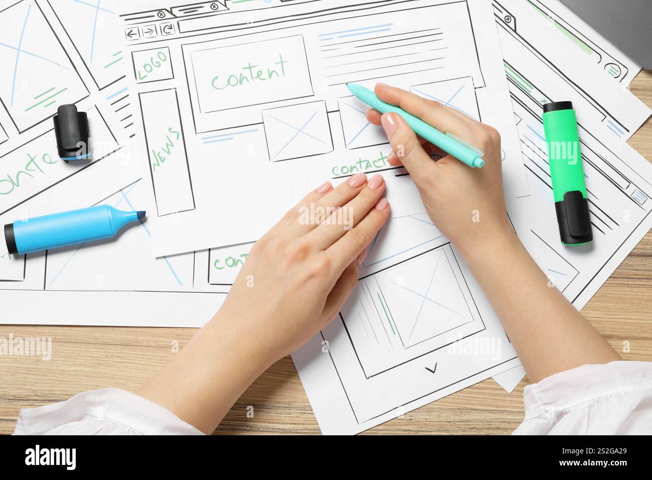 Website designer creating wireframe on paper with pen at wooden table ...