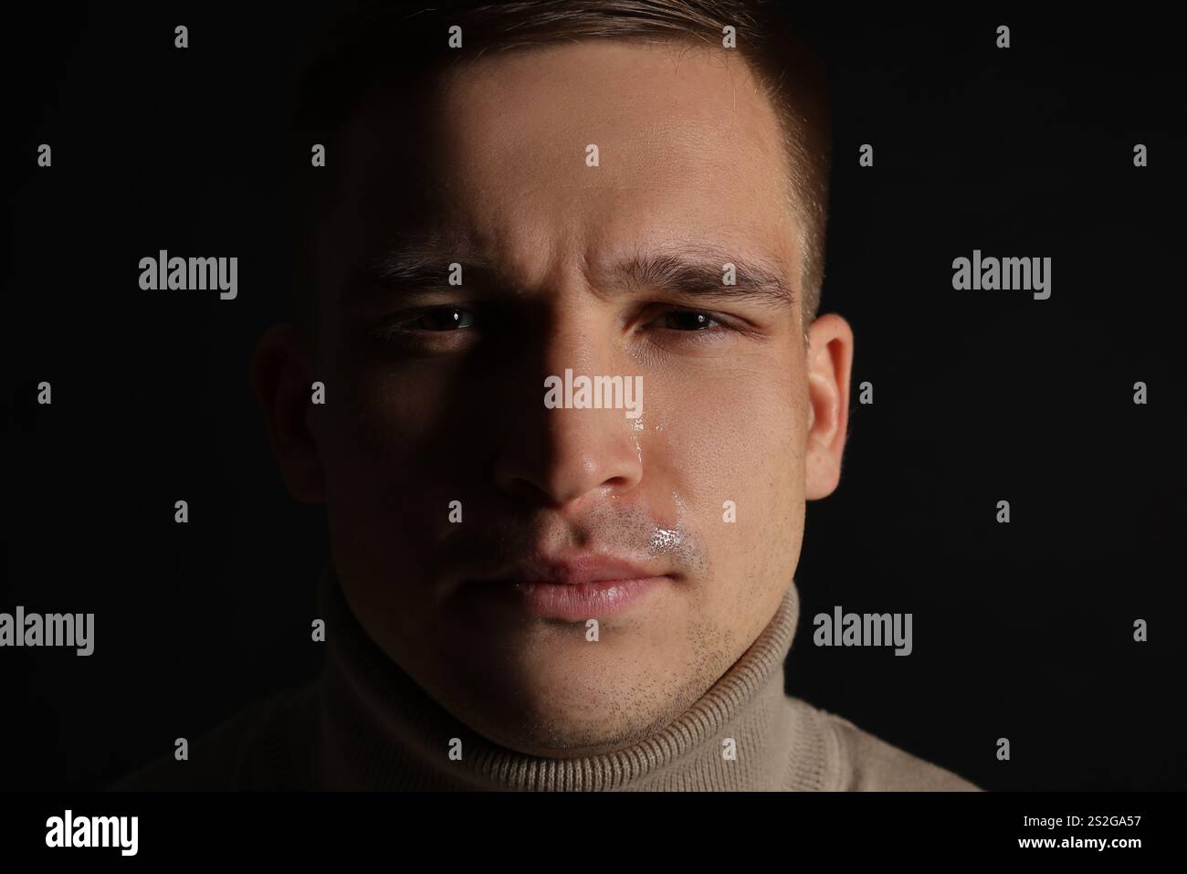 Distressed young man crying on black background, closeup Stock Photo ...