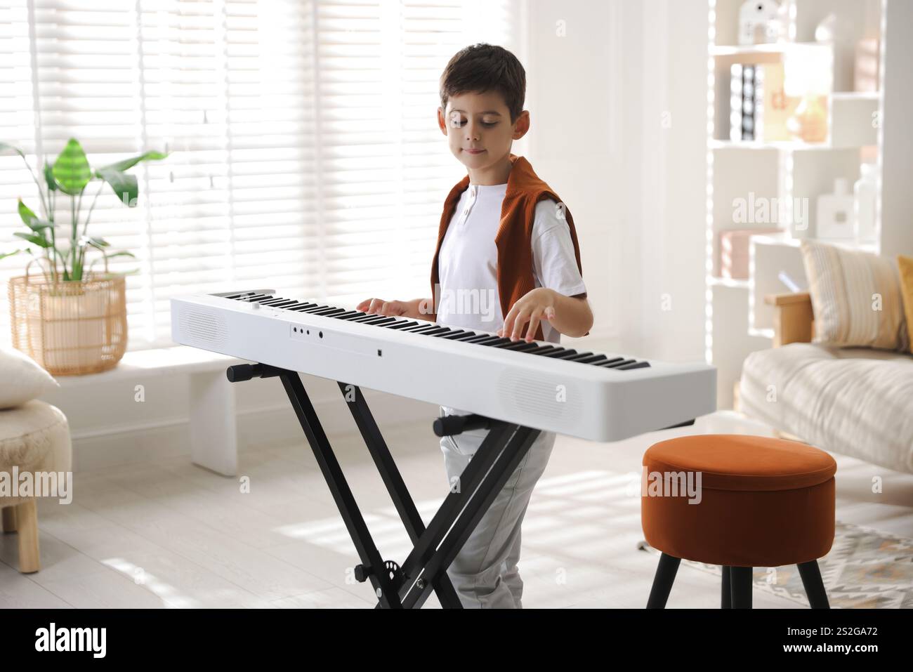 Cute boy playing synthesizer at home. Electronic musical instrument ...