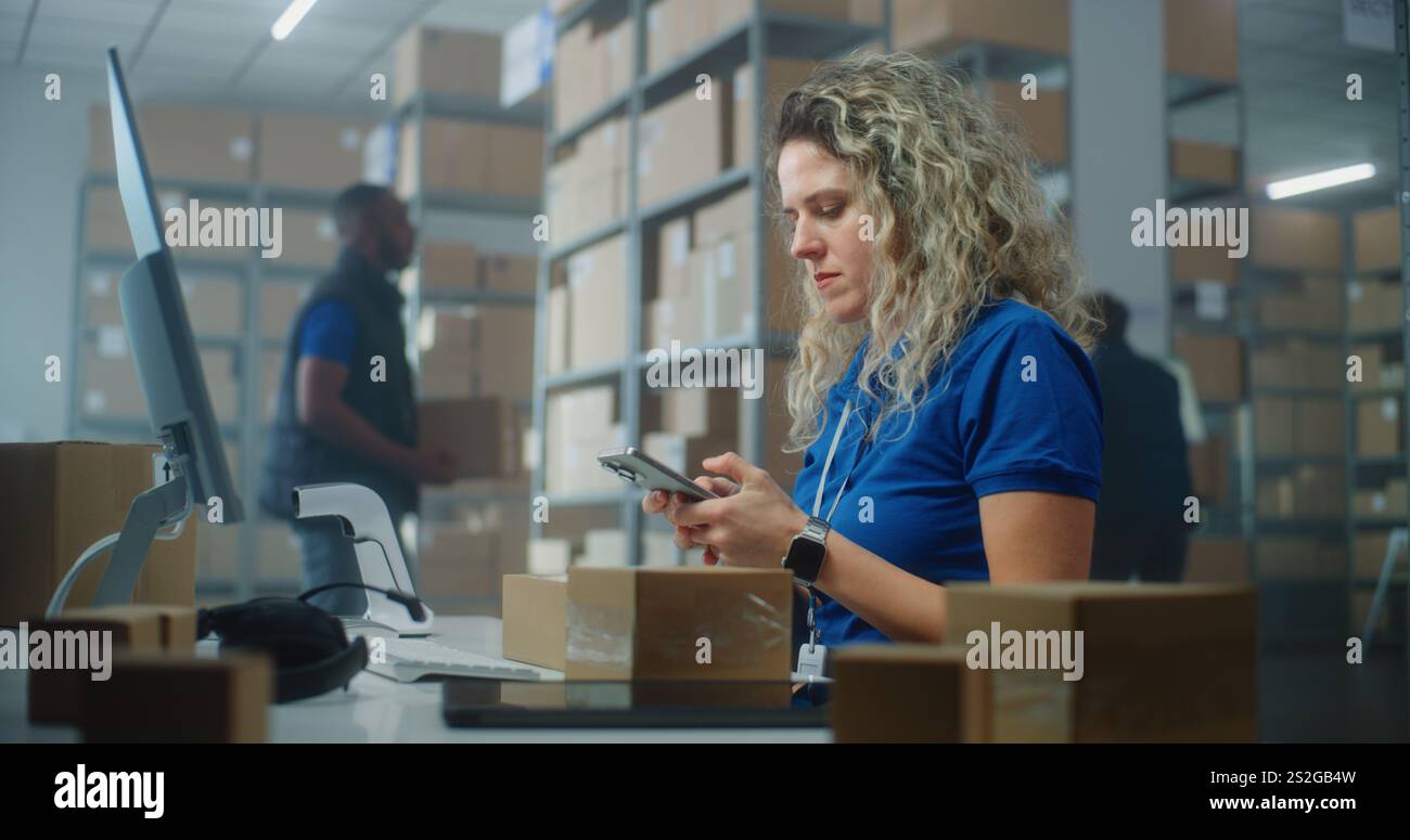 Female logistics manager scans small parcels using smartphone, works in warehouse of postal ...