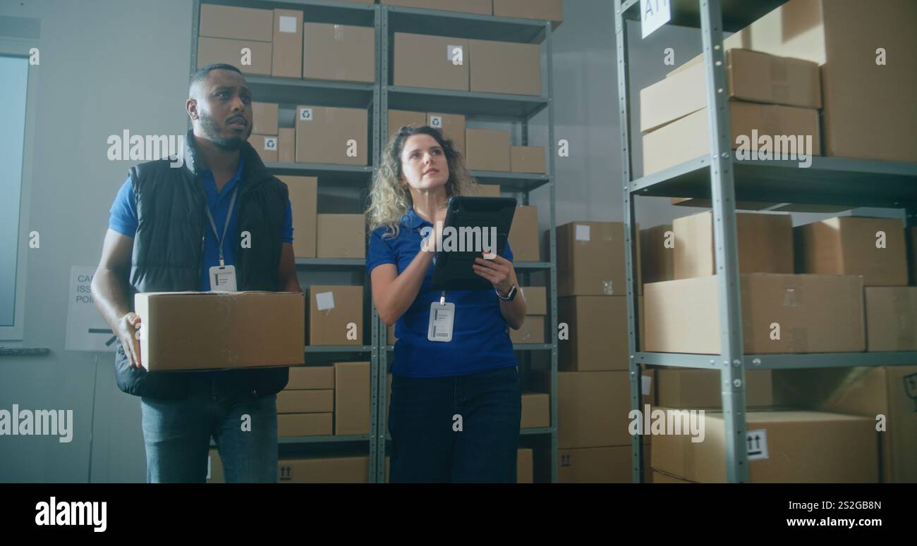 Female inventory manager walks with colleague, uses tablet computer ...