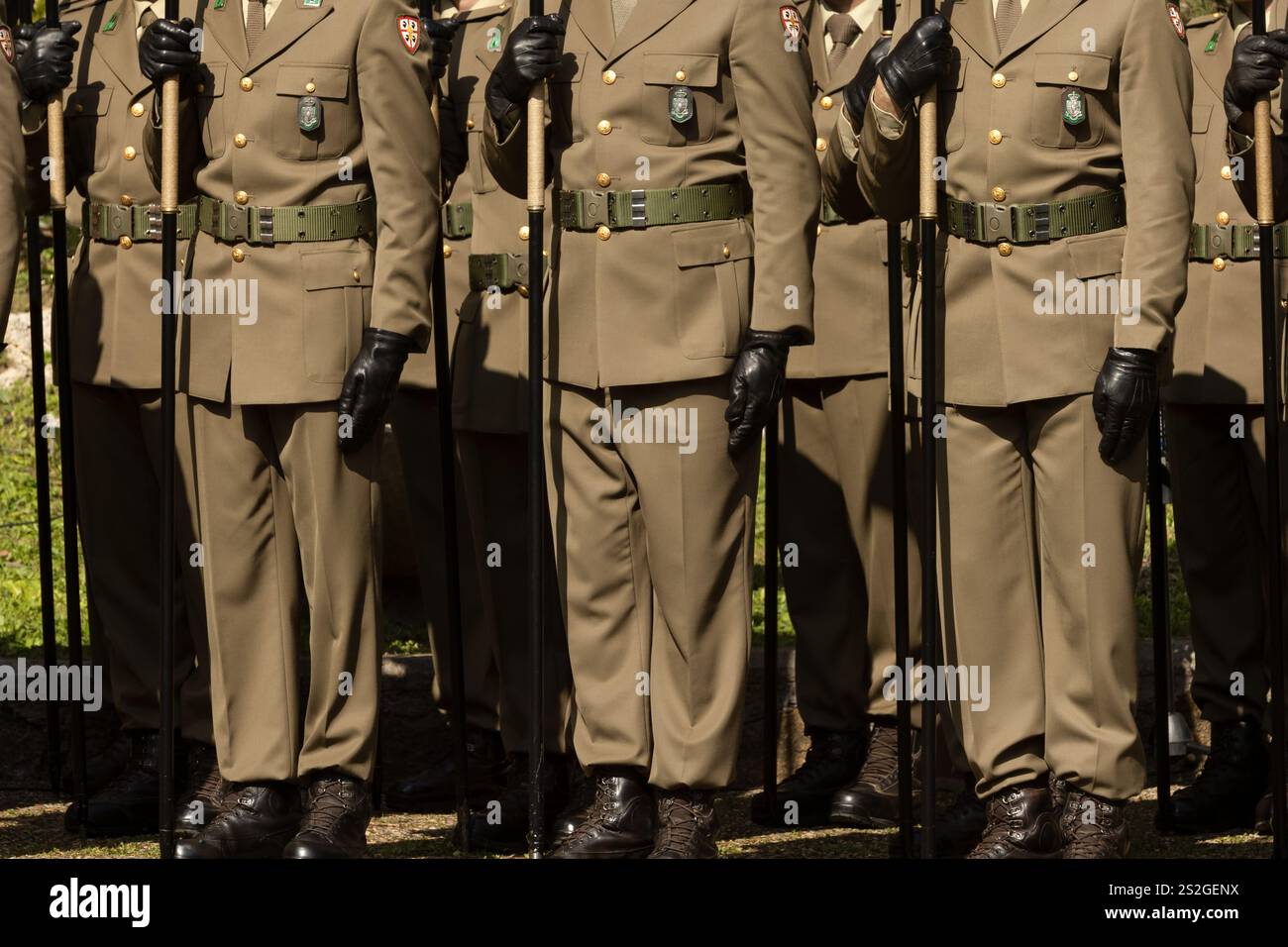 Uniformed soldiers in ceremonial stance holding staffs in outdoor ...
