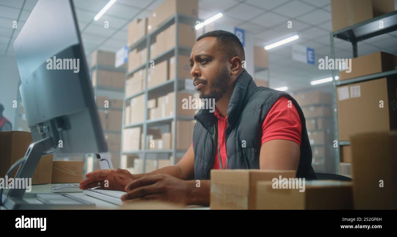 African American post office employee scans cardboard parcel using barcode scanner, works on ...