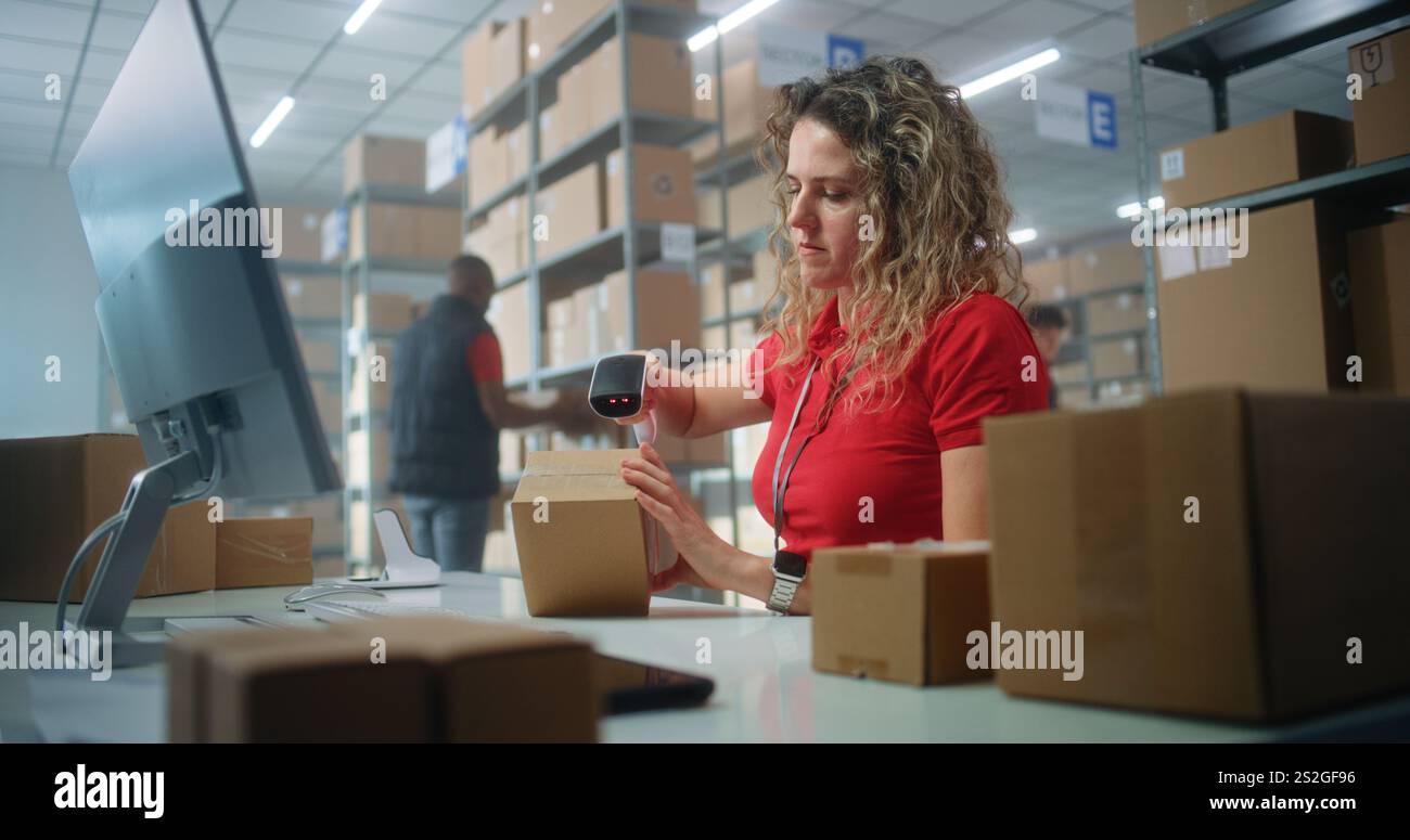 Female manager scans parcel using barcode scanner, enters data on computer. Sorting center ...