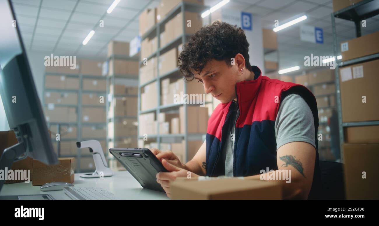 Male warehouse clerk scans parcels using tablet computer, works in ...