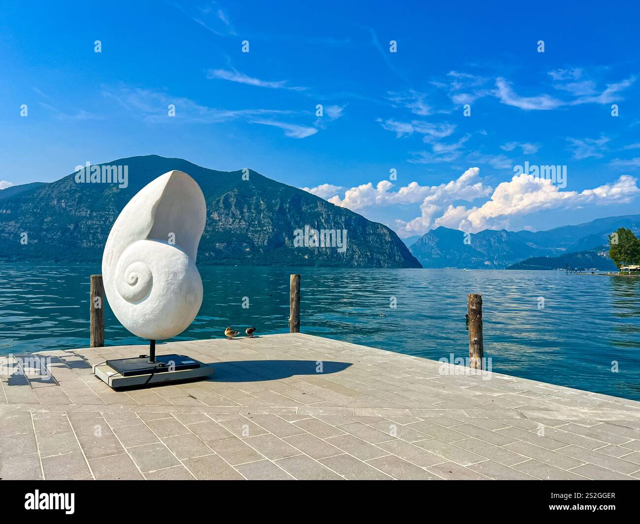 Abstract White Snail Shell Sculpture on a Stone Dock by a Calm Lake ...