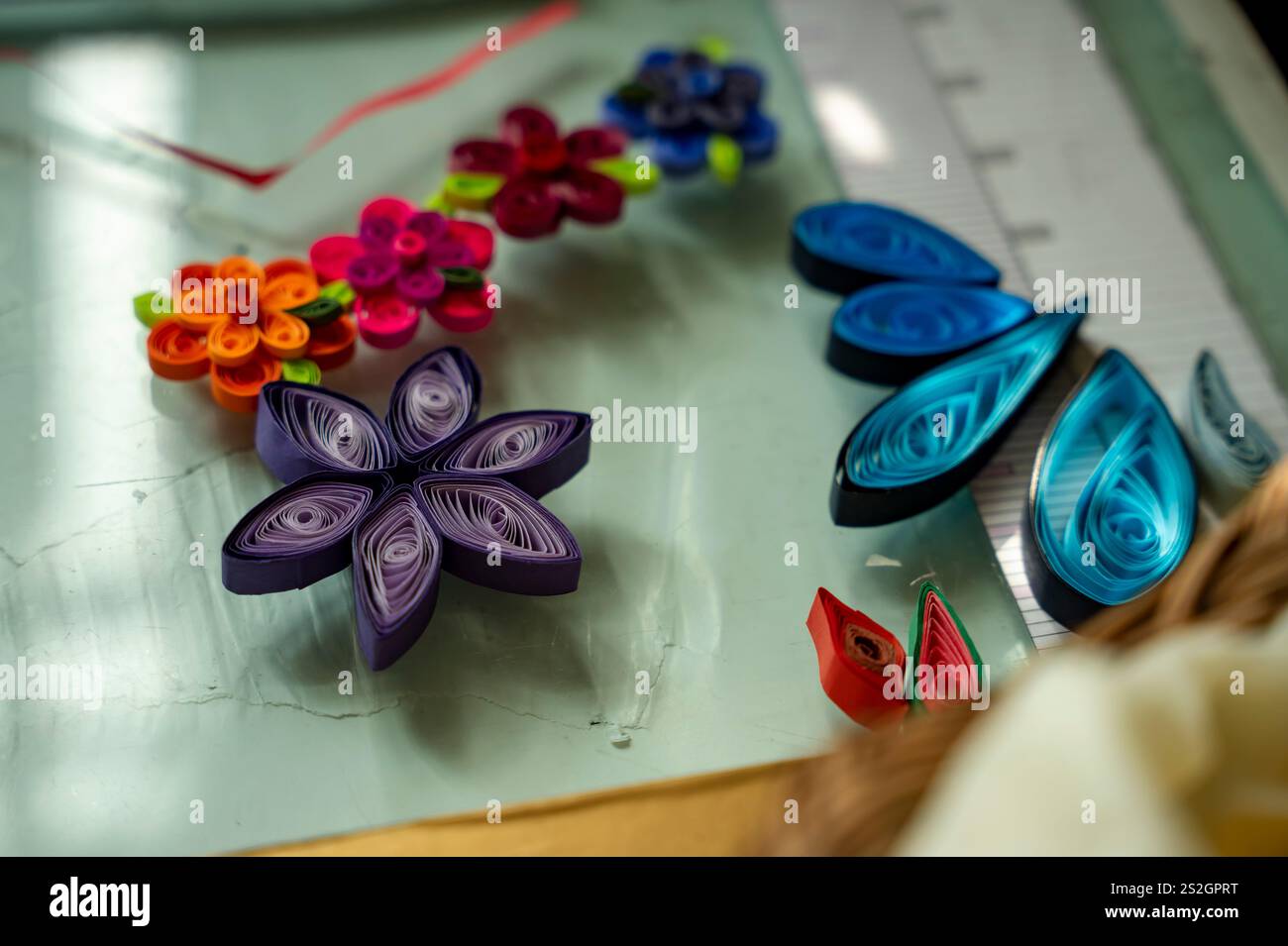 Flower designs crafted from quilling paper are seen at a home-based ...
