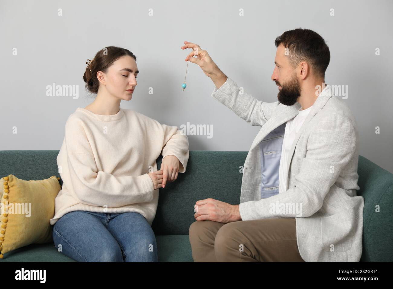 Psychologist using pendulum while working with patient during hypnosis ...