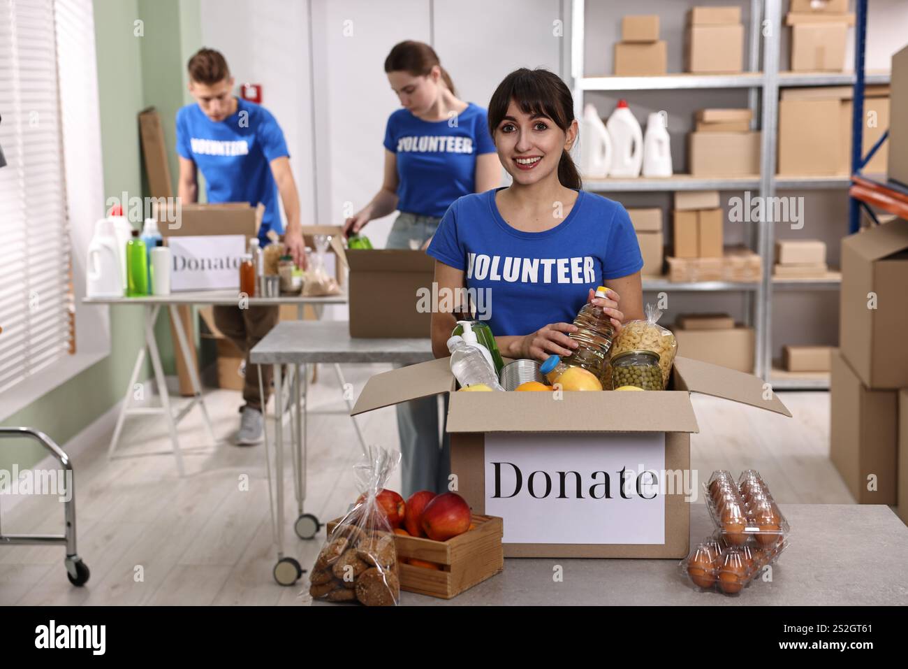 Volunteers packing food donations at tables indoors Stock Photo - Alamy