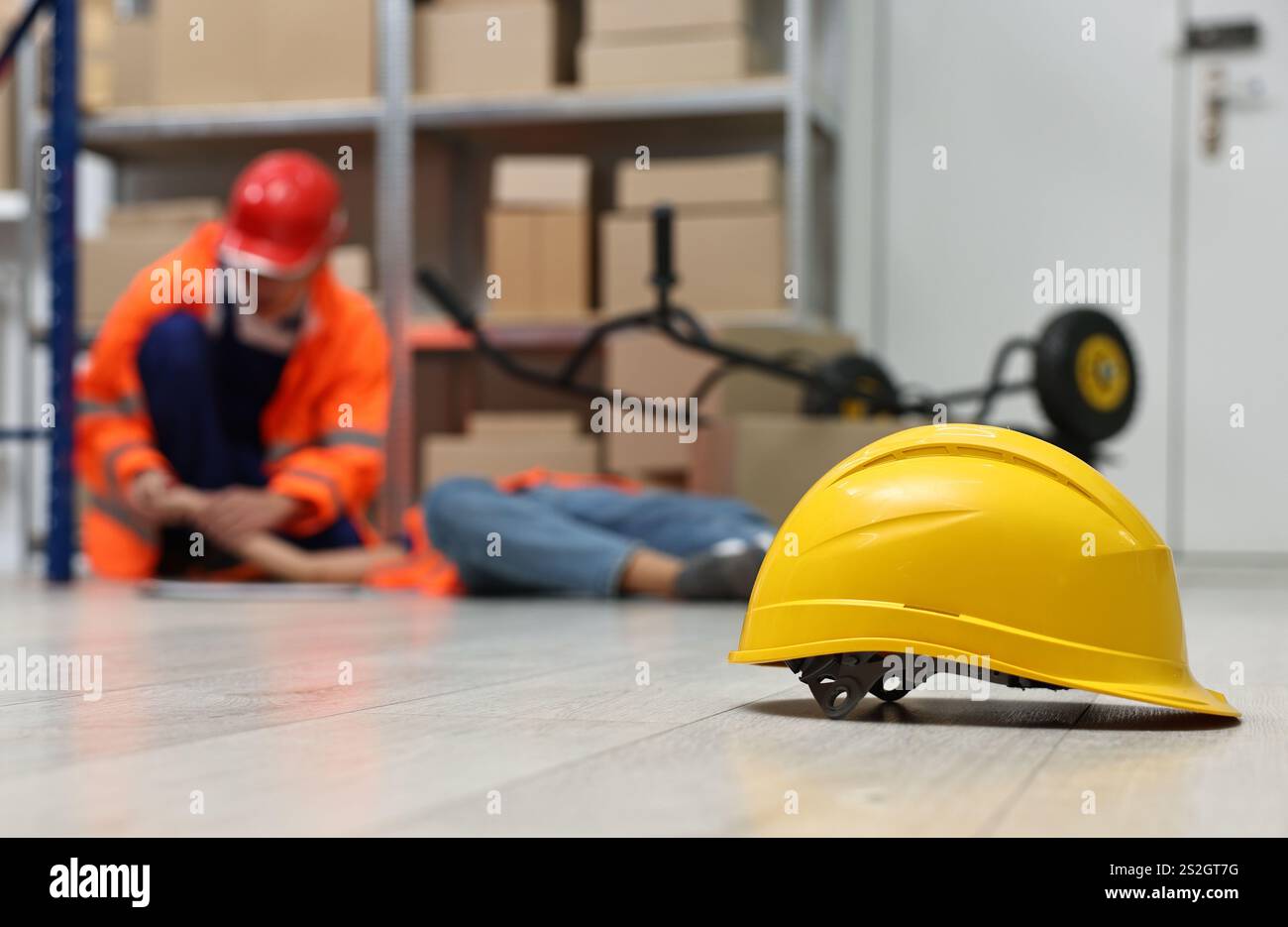 First aid. Hardhat on floor and man helping his unconscious colleague ...