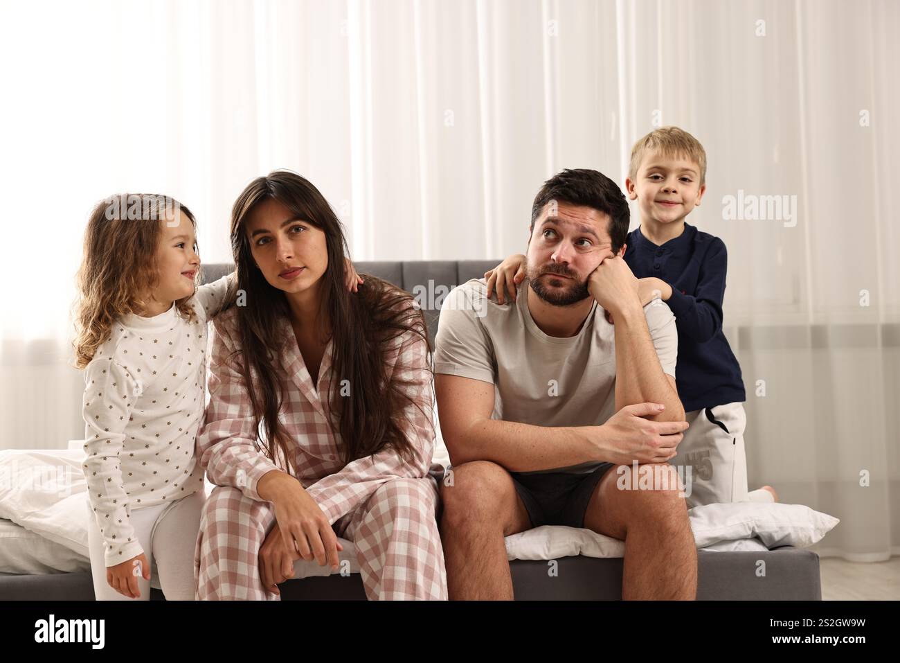 Playful children and their overwhelmed parents on bed at home Stock ...
