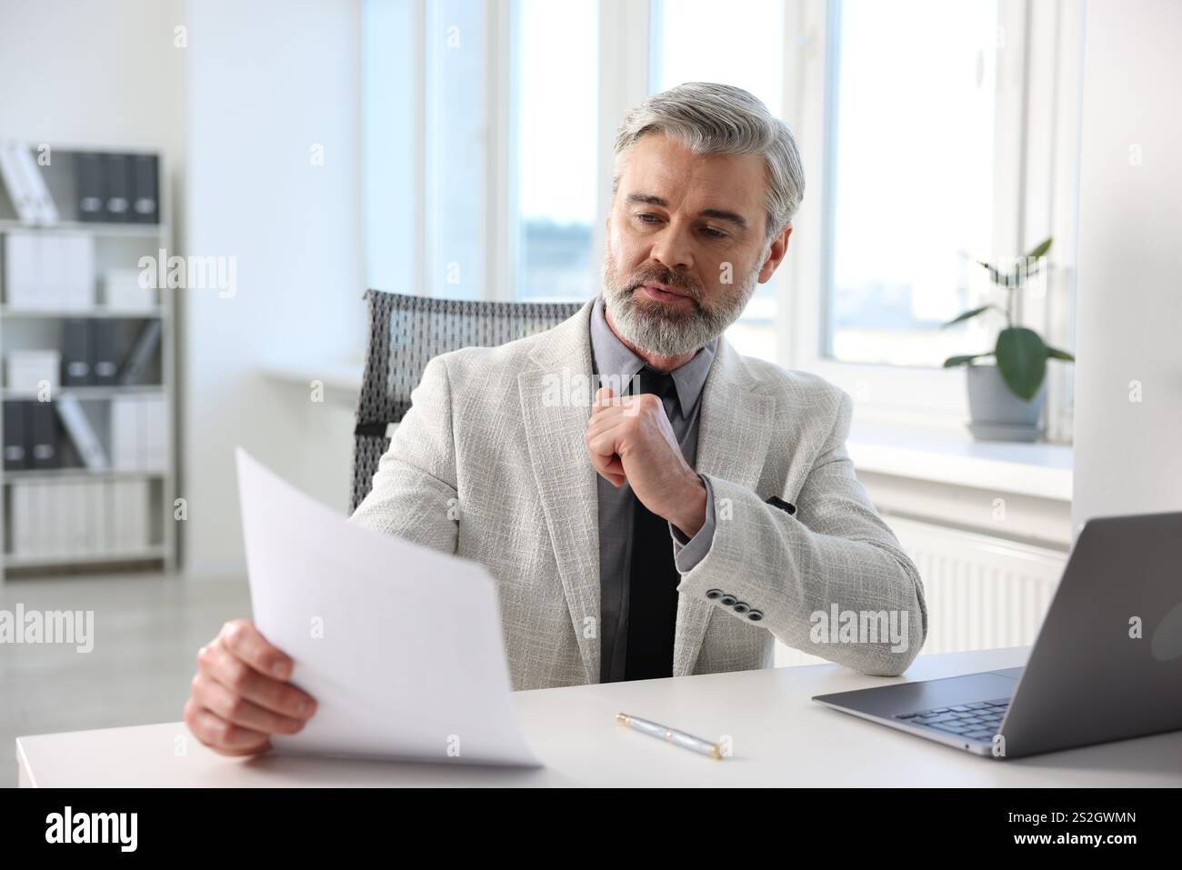 Banker with document at desk in office Stock Photo - Alamy