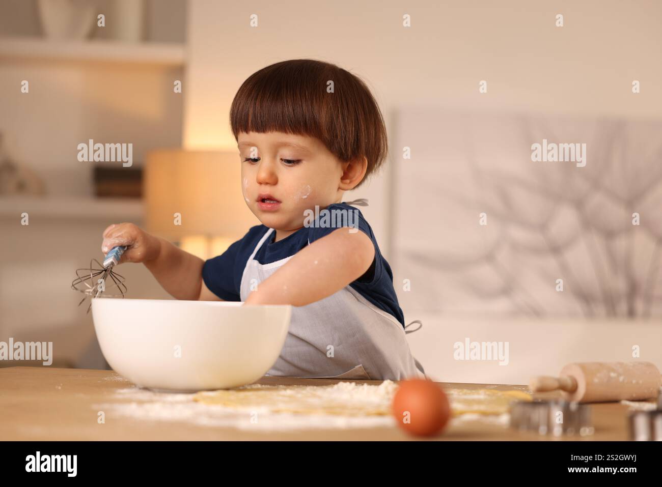 Cute little boy making dough at table indoors, space for text Stock ...