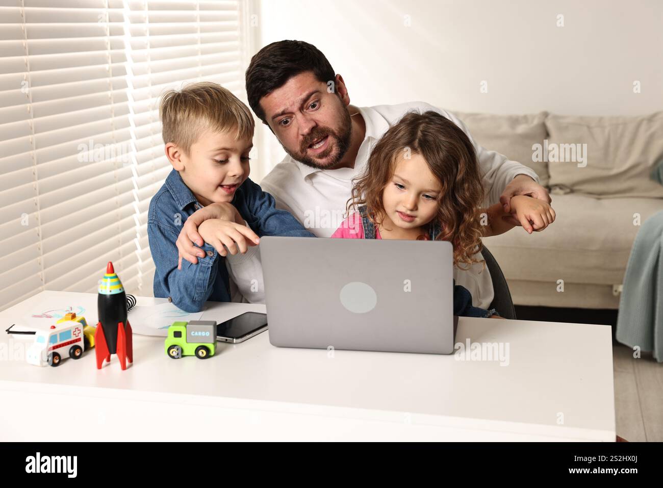 Naughty children disturbing their overwhelmed father at table with ...