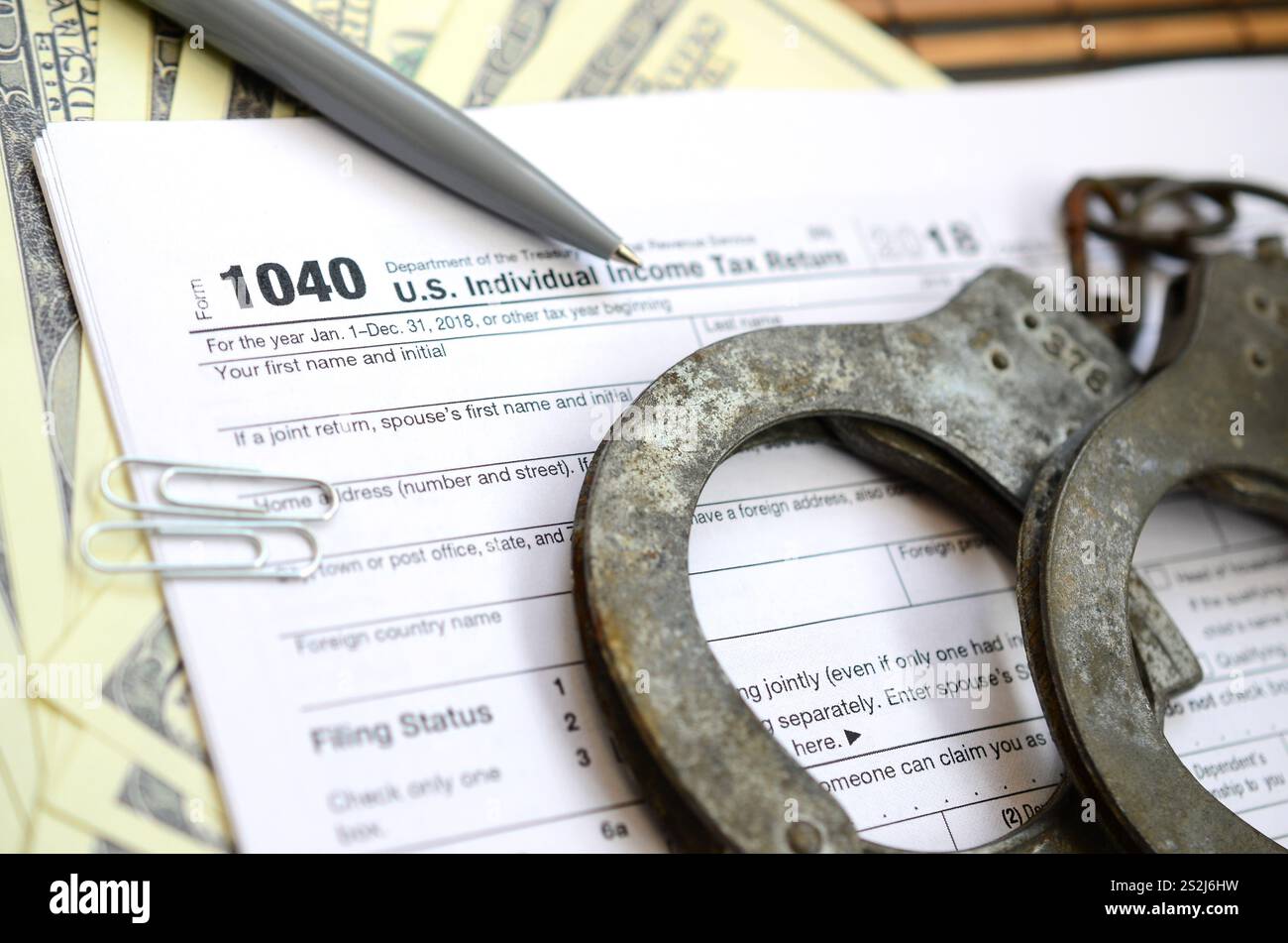 Police handcuffs lie on the tax form 1040. The concept of problems with ...