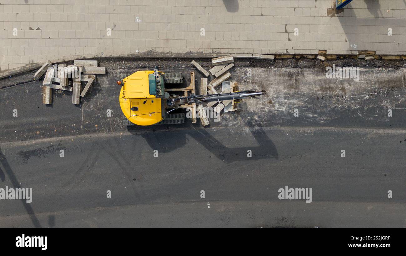 An aerial view of a yellow construction vehicle on a road, surrounded ...