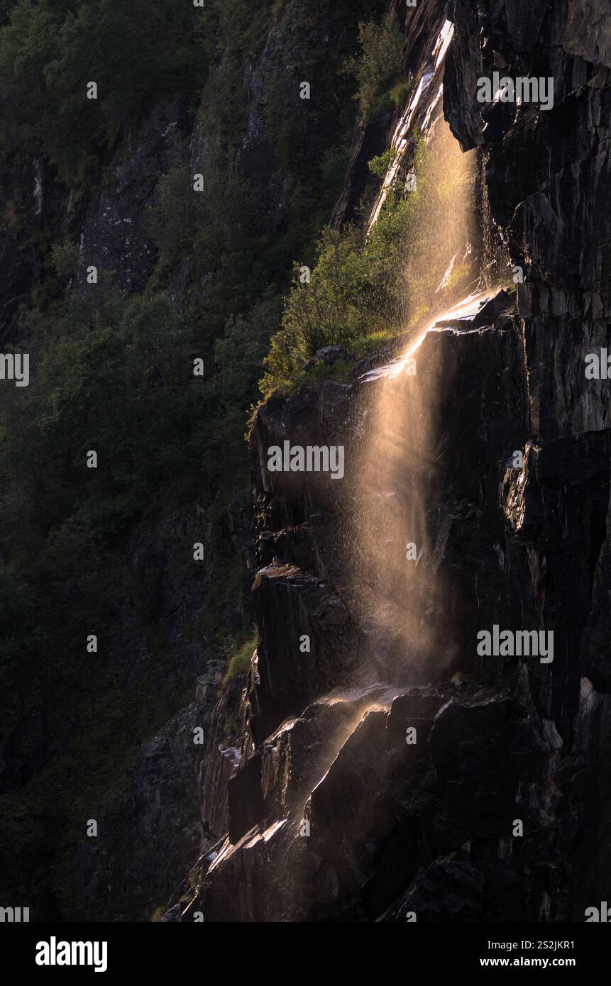 Dramatic scene of sunlight illuminating a gentle waterfall cascading ...
