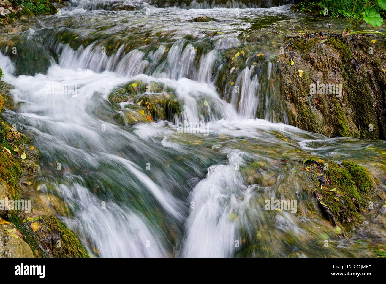 Low shutter speed shot of beautiful waterfall cascade from hiking trail ...