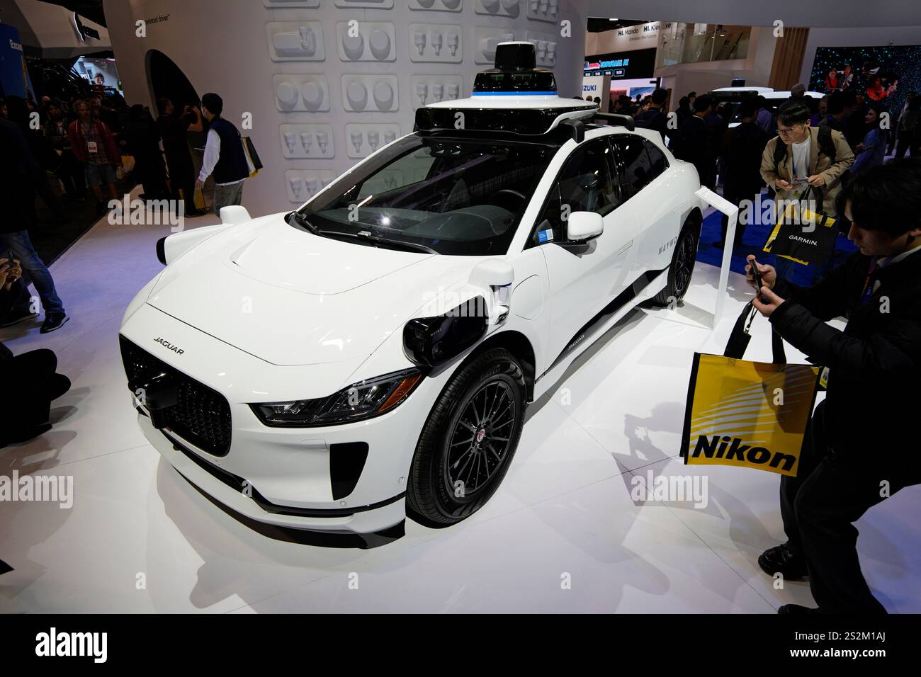 People look at a Jaguar I-Pace with 5th Generation Waymo Driver on ...
