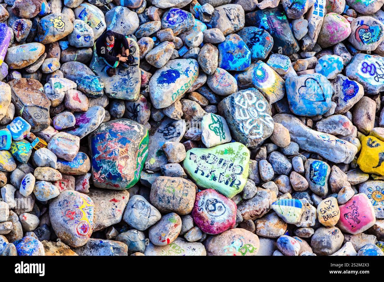 A pile of rocks with graffiti on them. The rocks are of different sizes ...