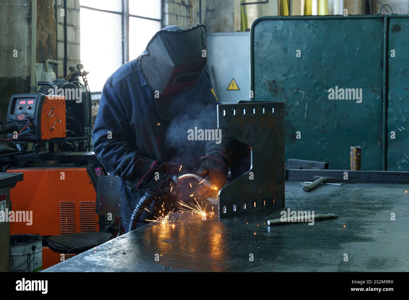 In a busy workshop, a dedicated worker skillfully welds metal parts ...