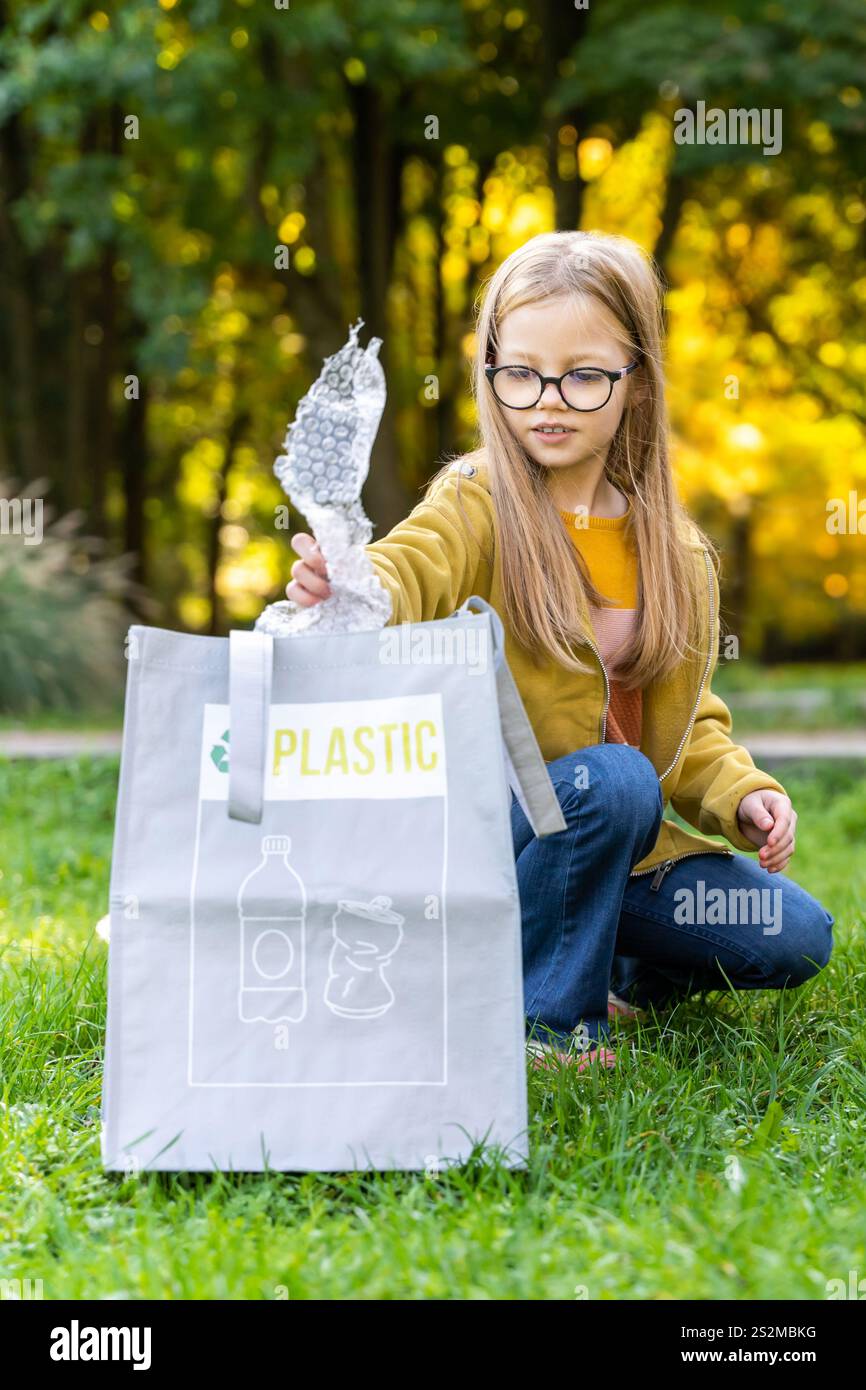 Little girl picking up trash outdoors sorting plastic waste into ...