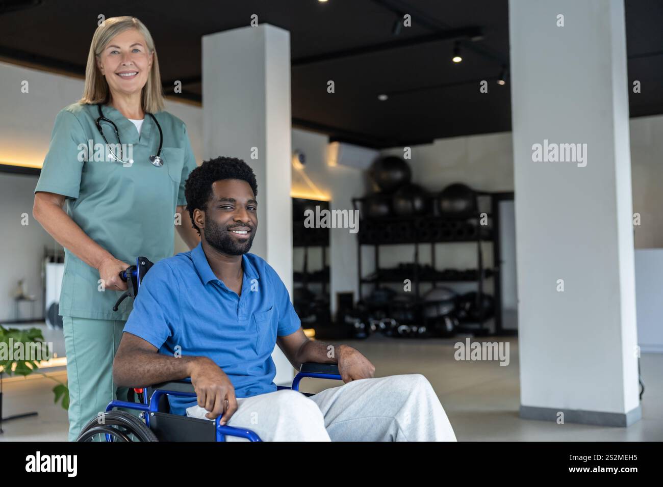 Doctor and a patient in a wheeling-chair looking contented and smiling ...