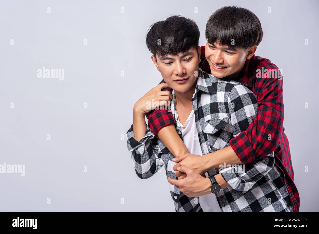 Two men who love each other hug from behind another Stock Photo - Alamy