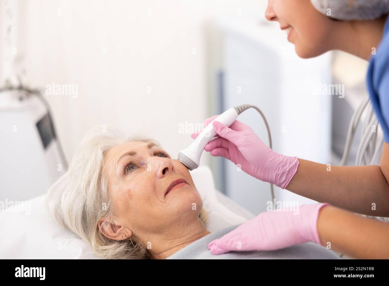 Mature female visitor receiving hardware electric lifting massage with ...