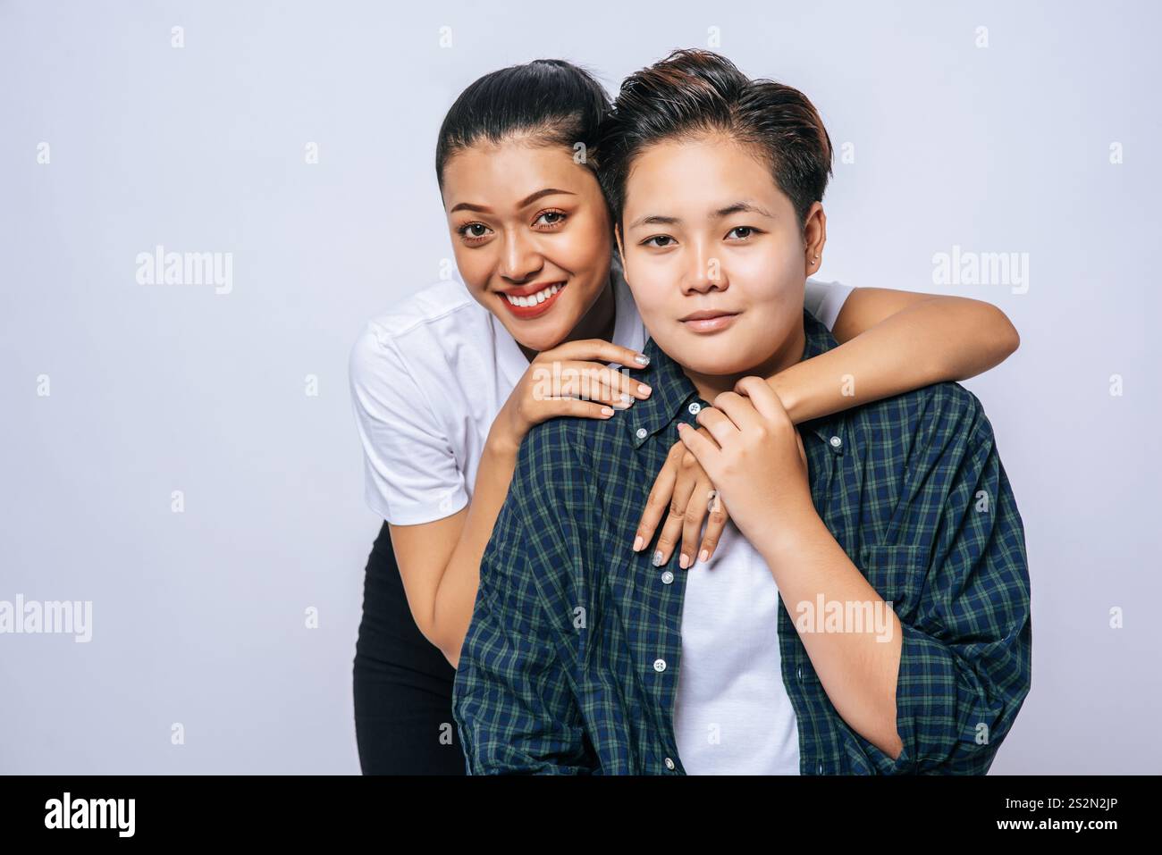 Two female lovers standing and hugging from behind Stock Photo - Alamy