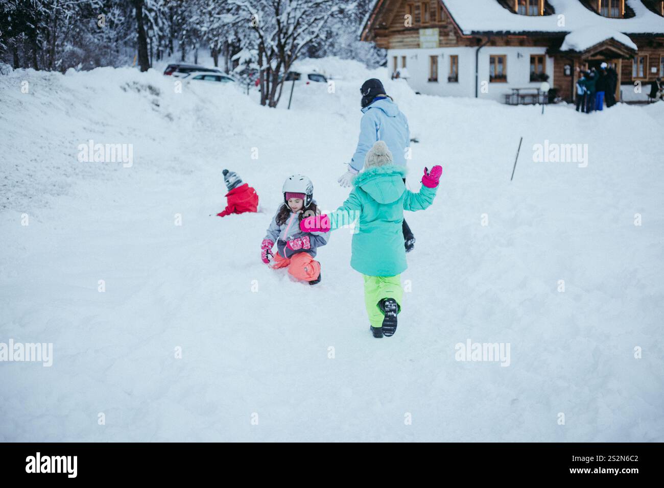 woman with three children playing on the snow together in front of big ...