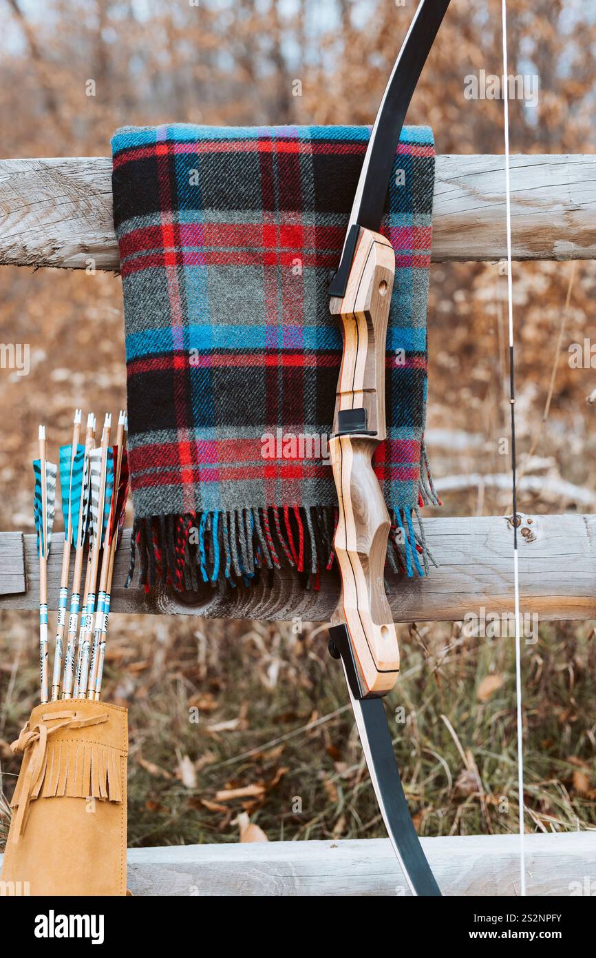 Archery bow and quiver of arrows leaning against wool blanket on wood ...