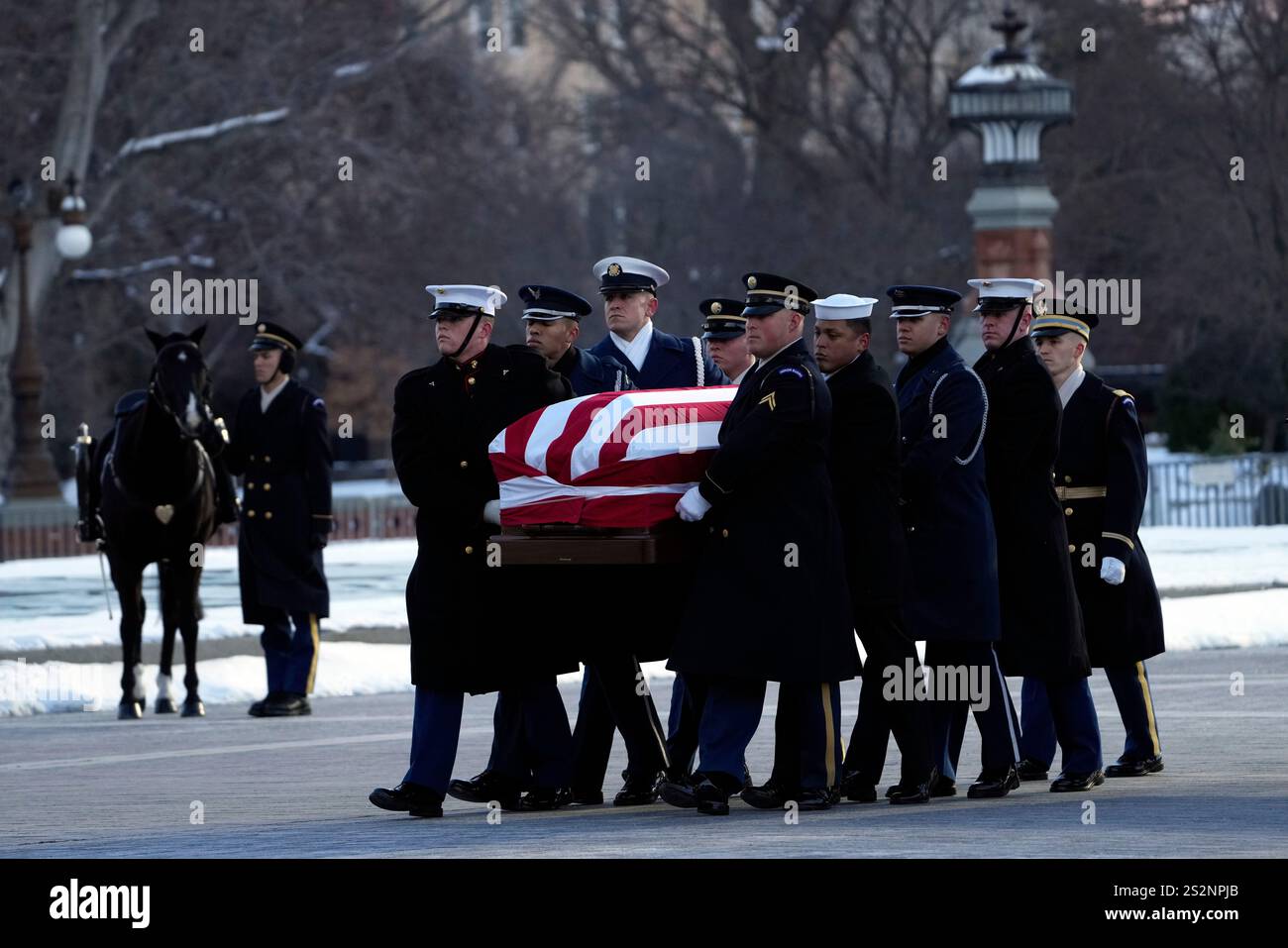 The flag-draped casket of former President Jimmy Carter is carried by a ...