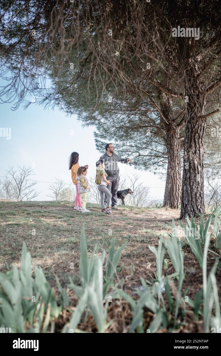 father with three daughters and a dog watching trees in the park Stock ...
