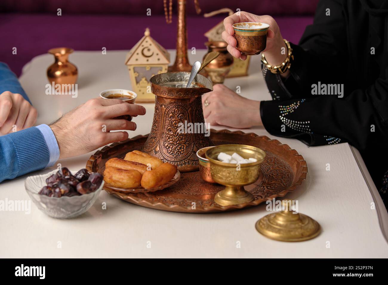 Happy Muslim family drinking traditional coffee with dessert at home ...