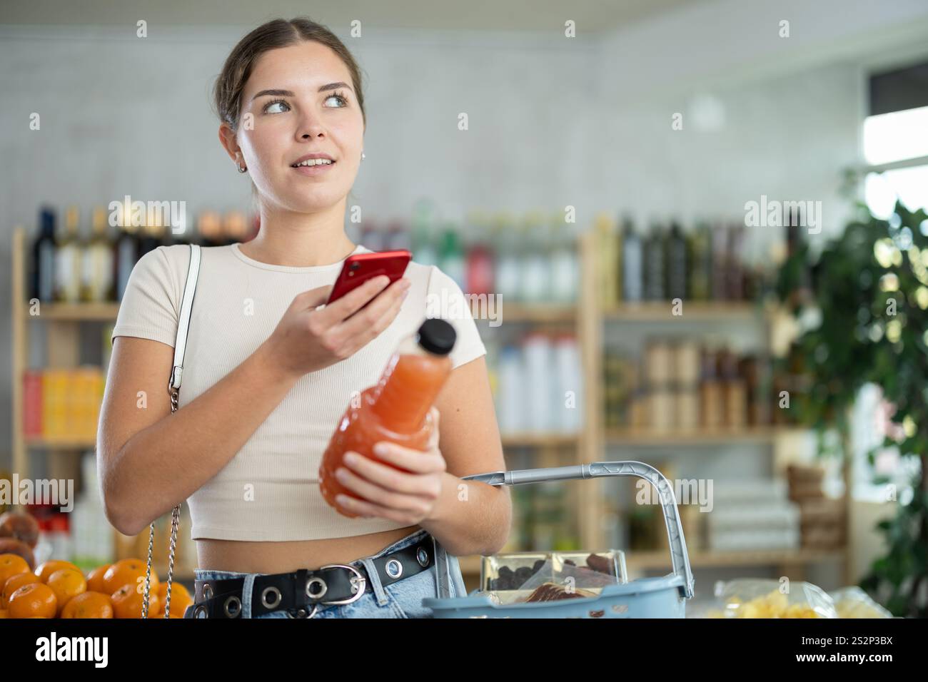 European young woman customer at shop scans QR code on grapefruit juice ...