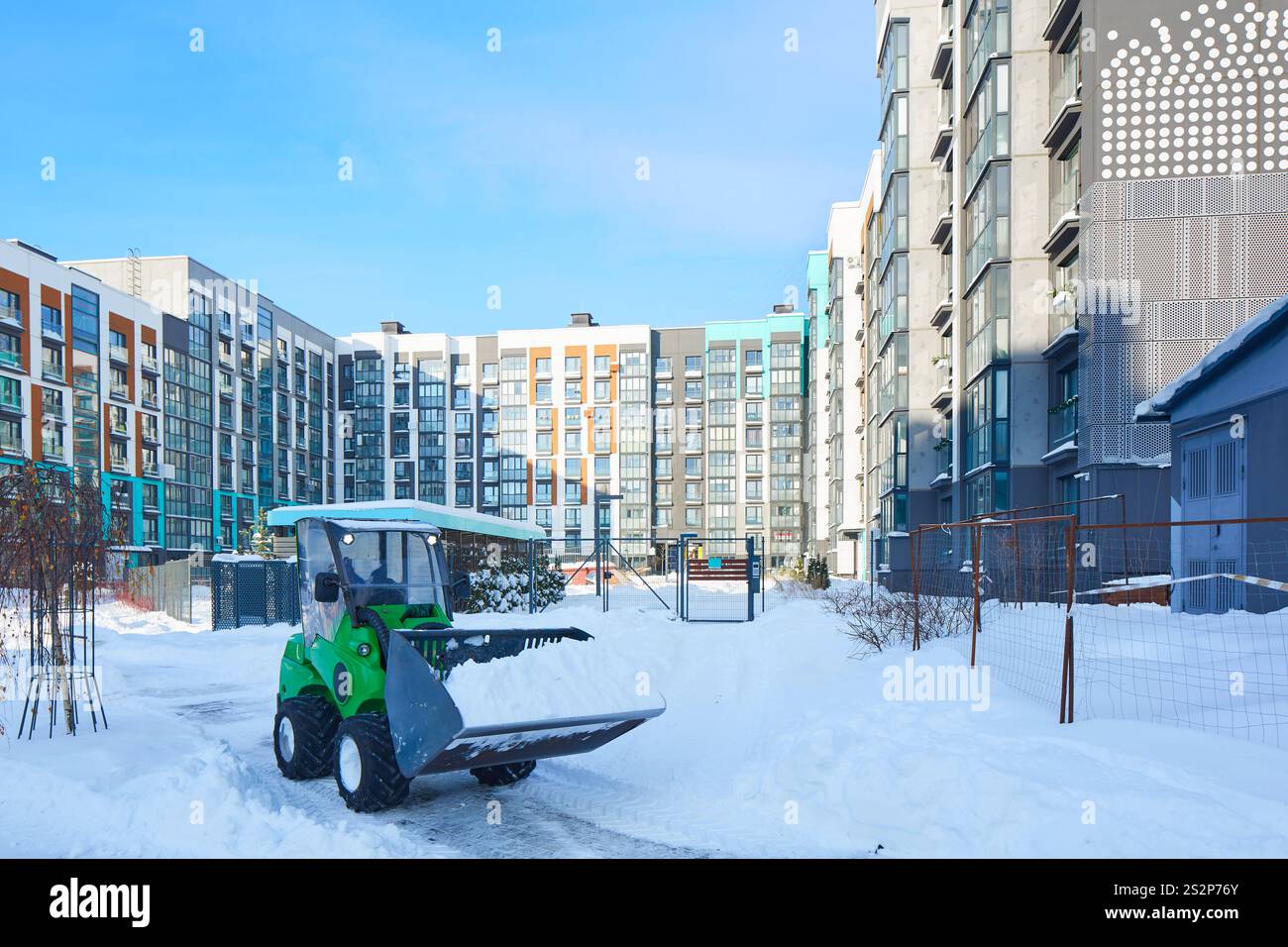 Snow cleaning tractor clears paths. snow removal machine in action. Front loader removes tons of ...