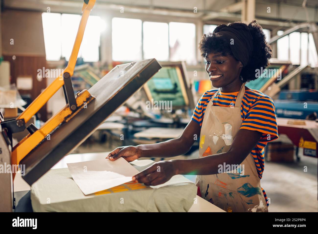 Happy multicultural printer woman preparing t-shirt for heating press ...