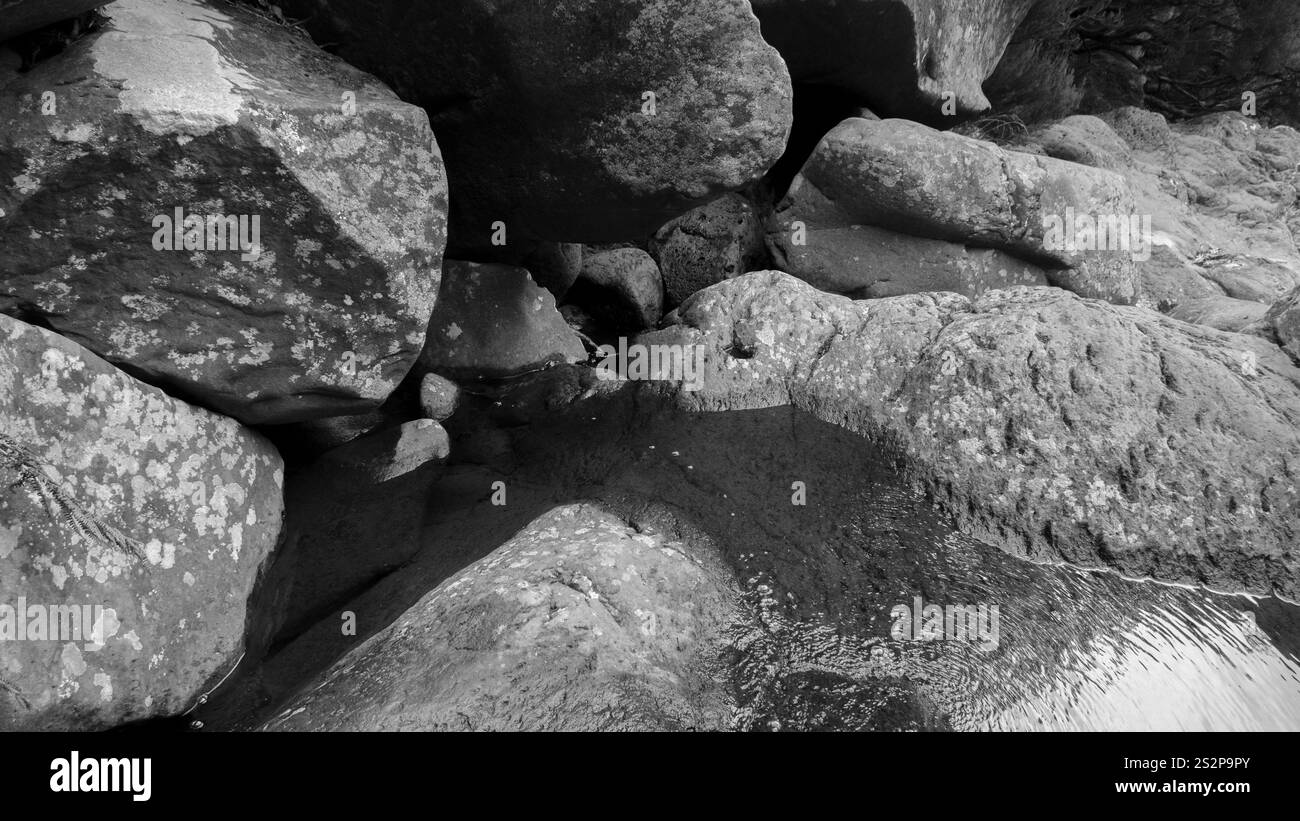 A black and white photograph of rugged rocks surrounding a small ...